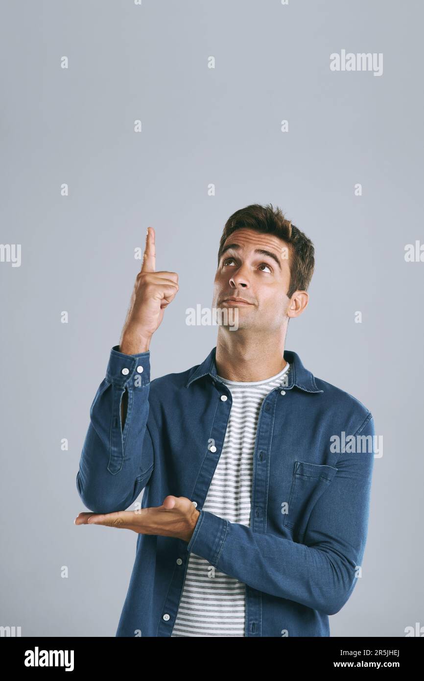 Its up there. a man pointing up against a grey background Stock Photo ...