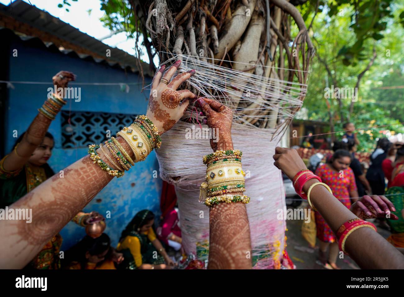 Married Hindu women tie a cotton thread around a Banyan tree as they ...