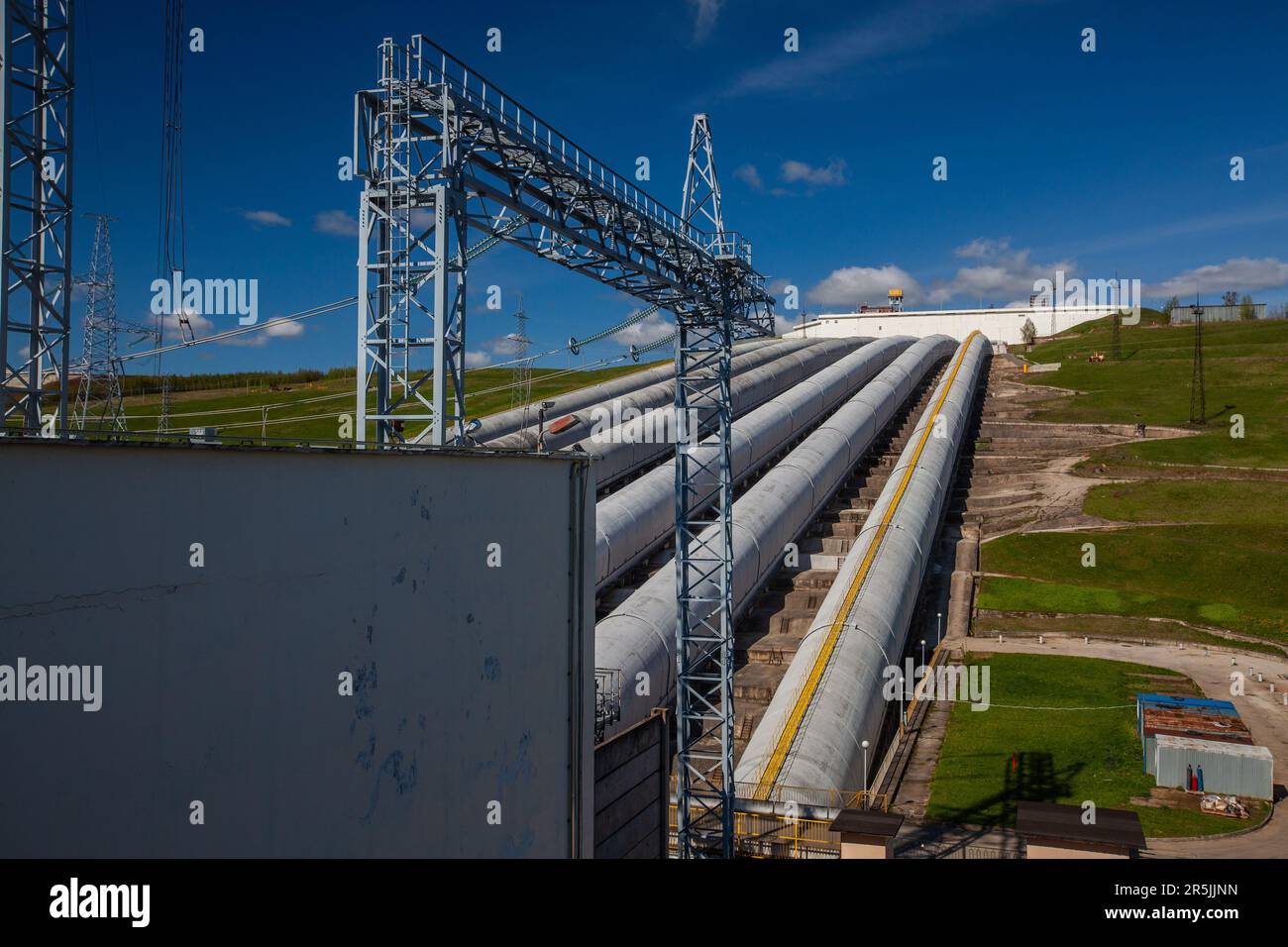 Hydro power plant pipes (right) and electric mast on blue sky ...