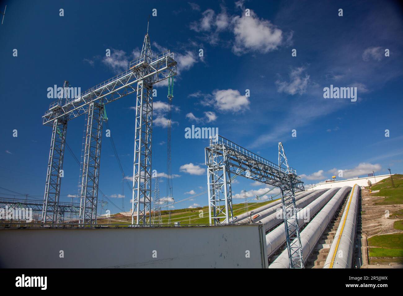 Hydro power plant pipes (right) and electric towers on blue sky ...
