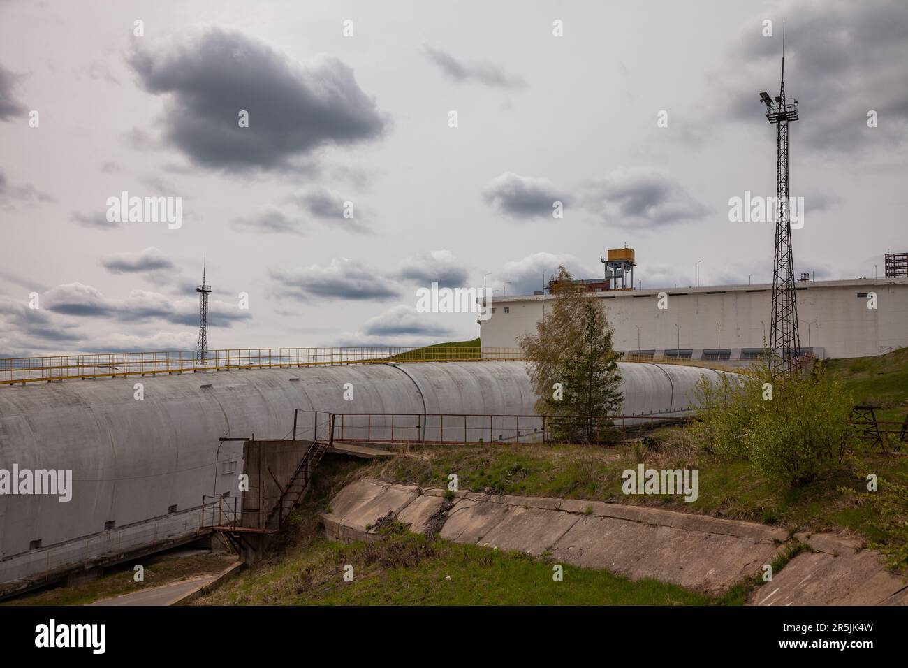 Water pipes of hydro power plant and metal masts on grey sky background ...