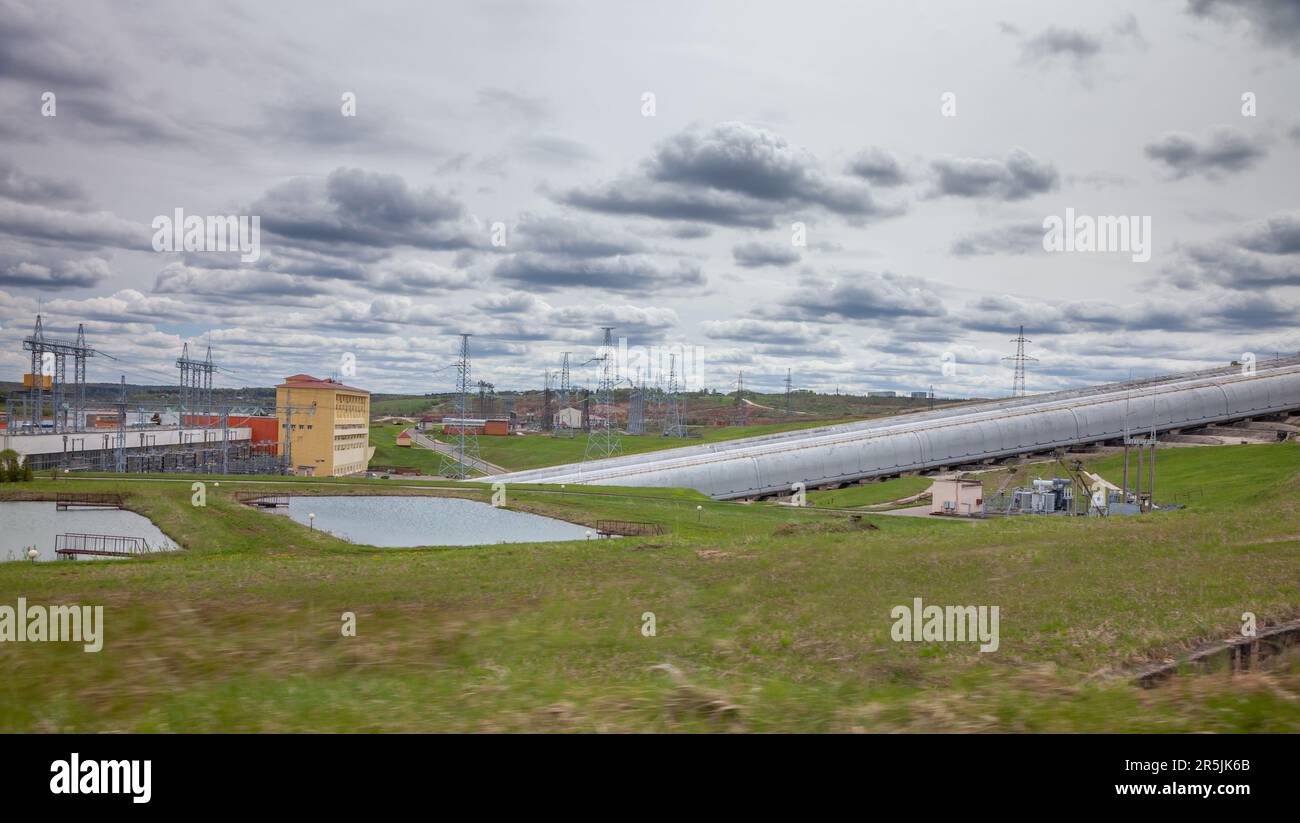 Hydro power plant ponds and pipes and machine building on grey sky ...