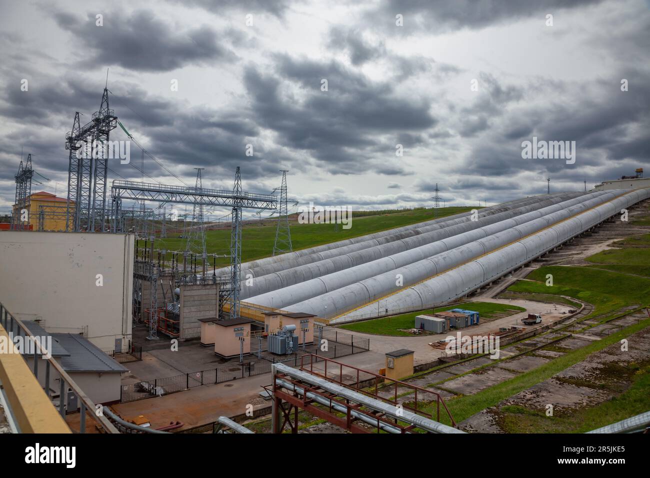 hydro power plant pipes and electric substation on grey sky background ...