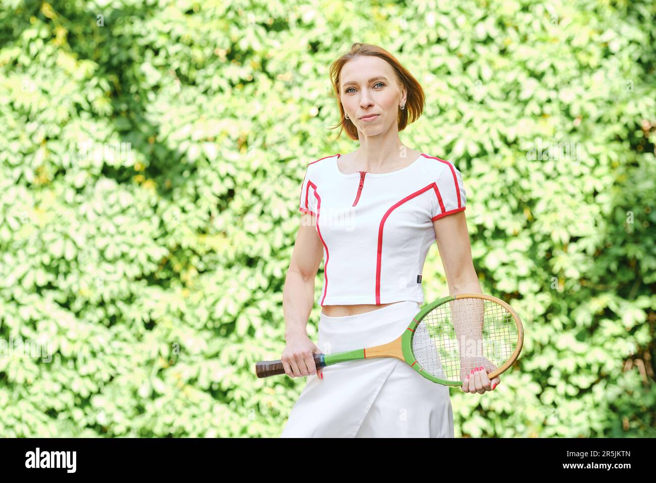 Adult redhead woman in tennis outfit posing with tennis racket Stock ...
