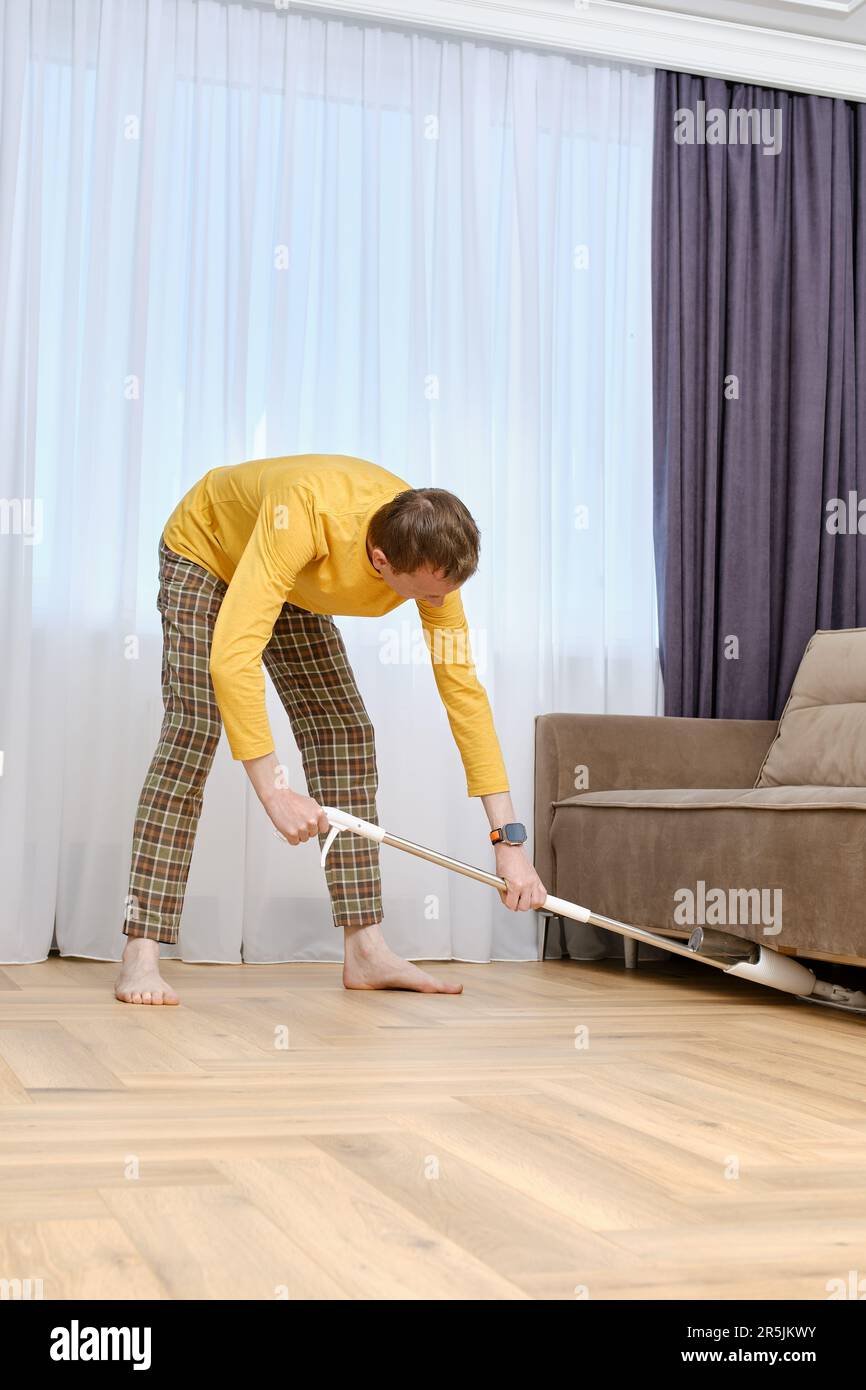 Single middle age man mopping floors under the sofa Stock Photo - Alamy