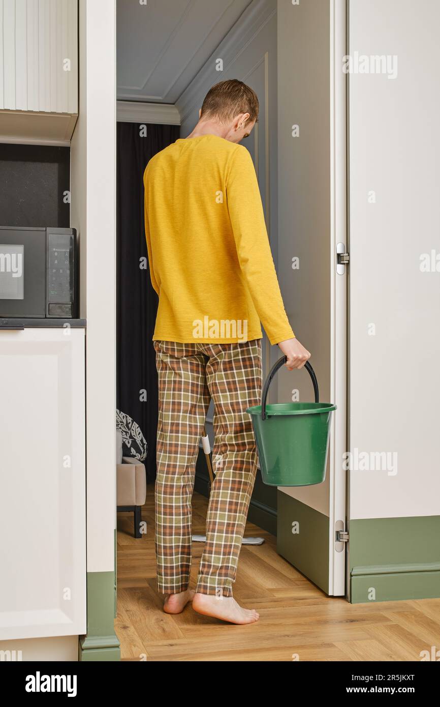 Back view of middle age man with mop and bucket entering bedroom Stock ...