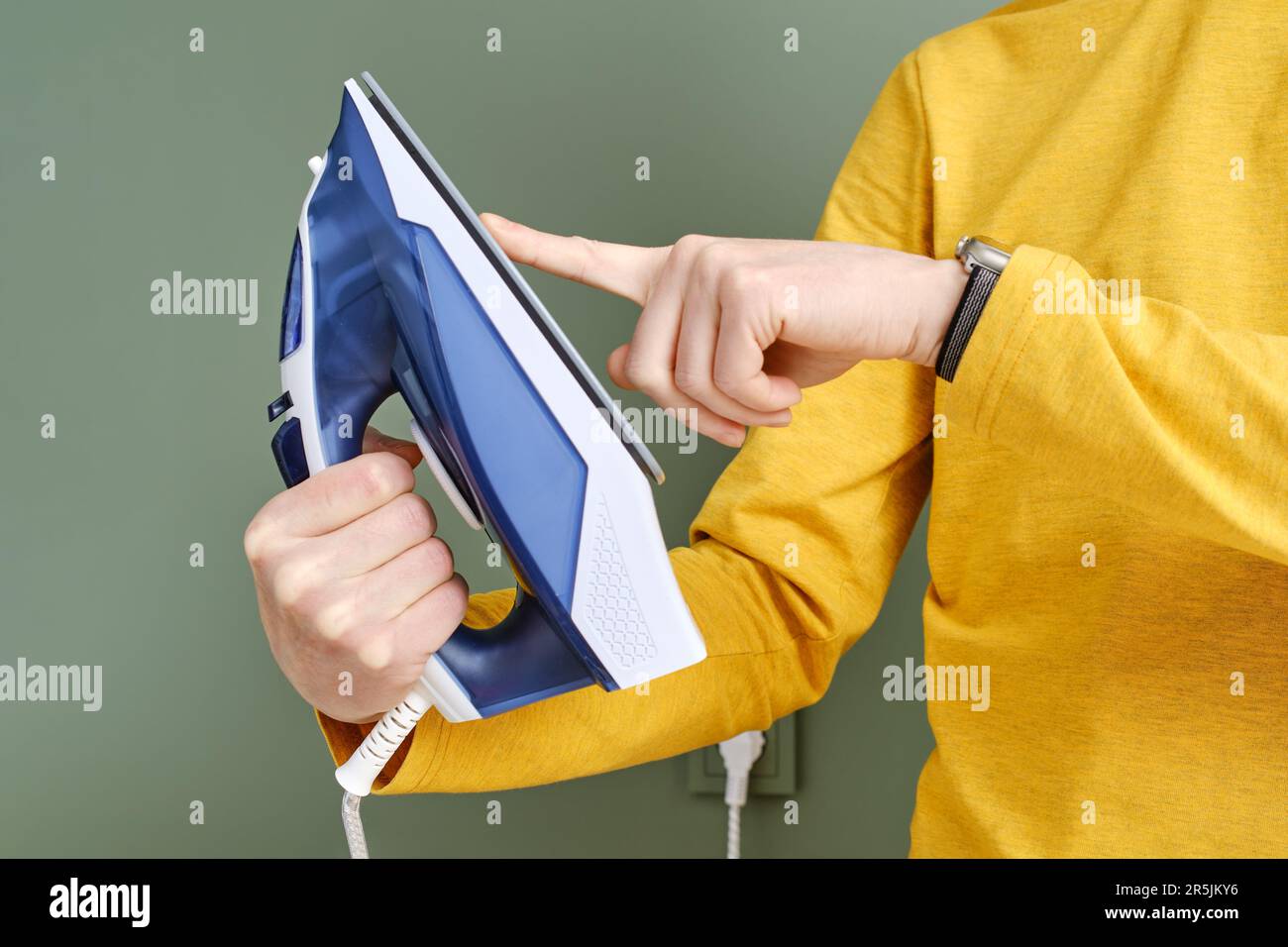 Unrecognizable man touching the sole of an iron with finger Stock Photo ...