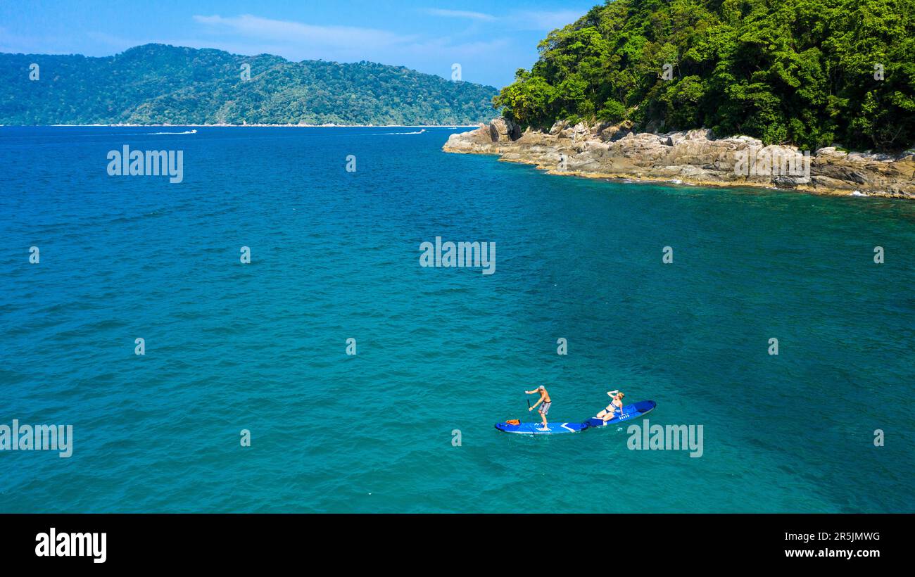 Ocean lovers in their element. a man and woman paddle boarding across ...