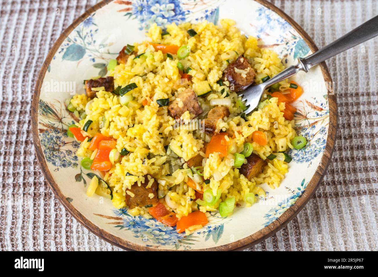 Turmeric rice with green onion, orange pepper and tempeh on decorative ...