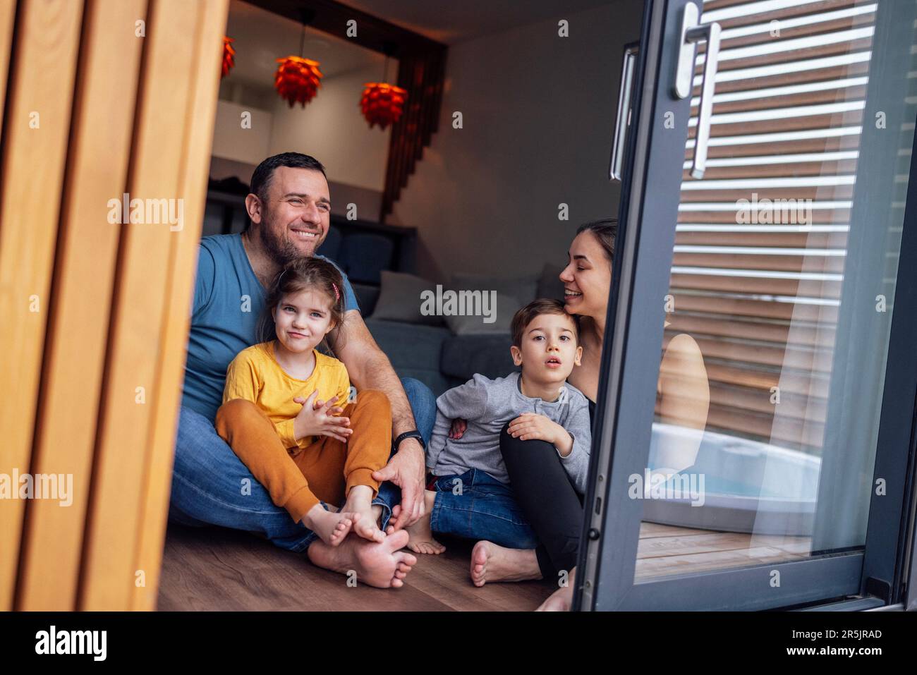 Young parents and small children sit on floor of living room at home in ...