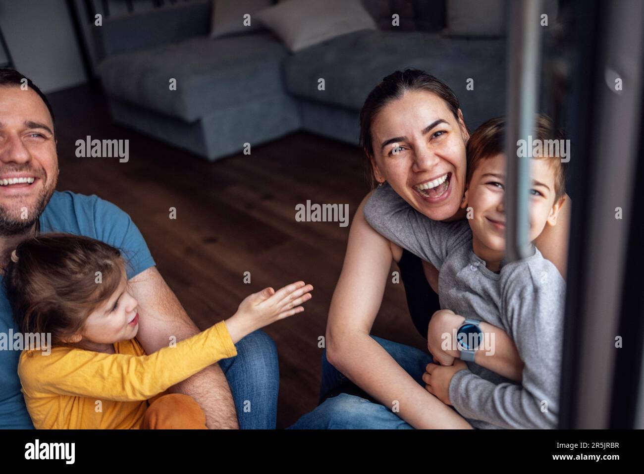 Young parents and small children sit on floor of living room at home in ...