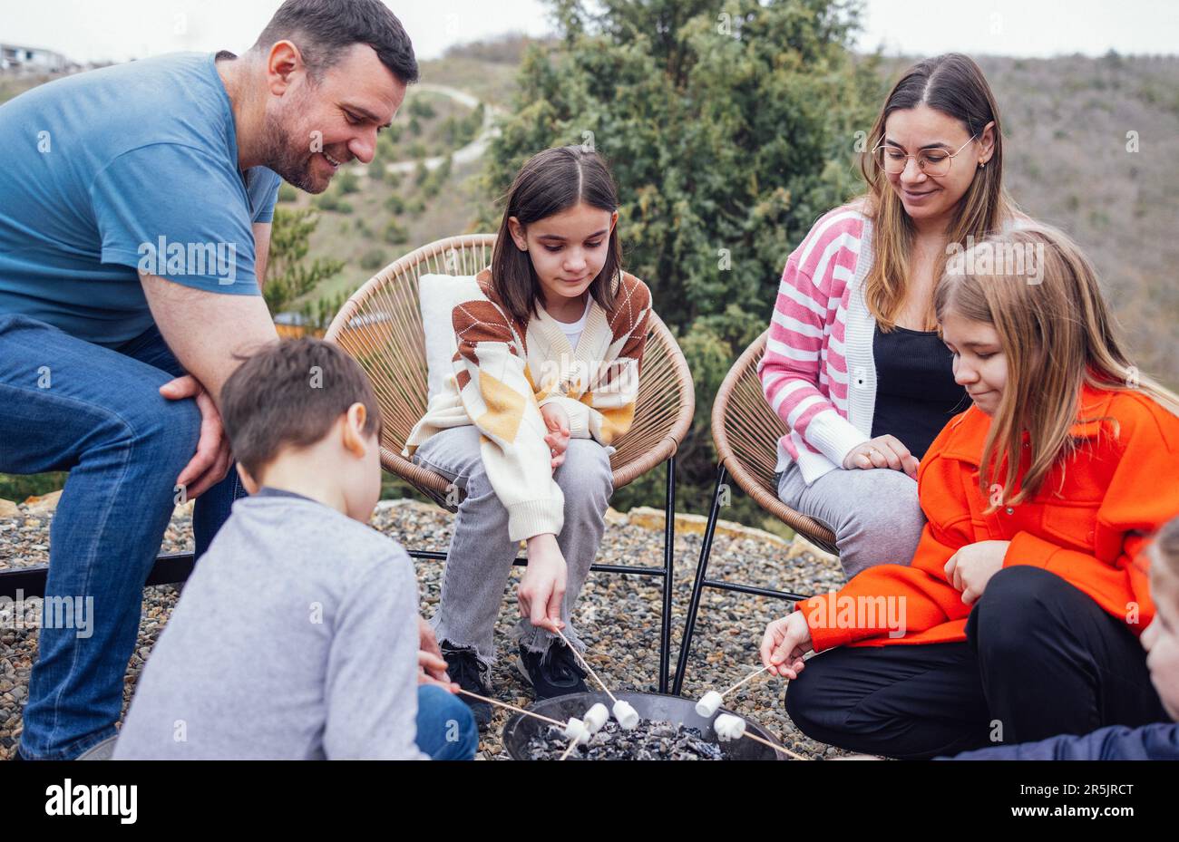 Big happy family roasting mashmallows outdoors. Young mom, dad, three ...