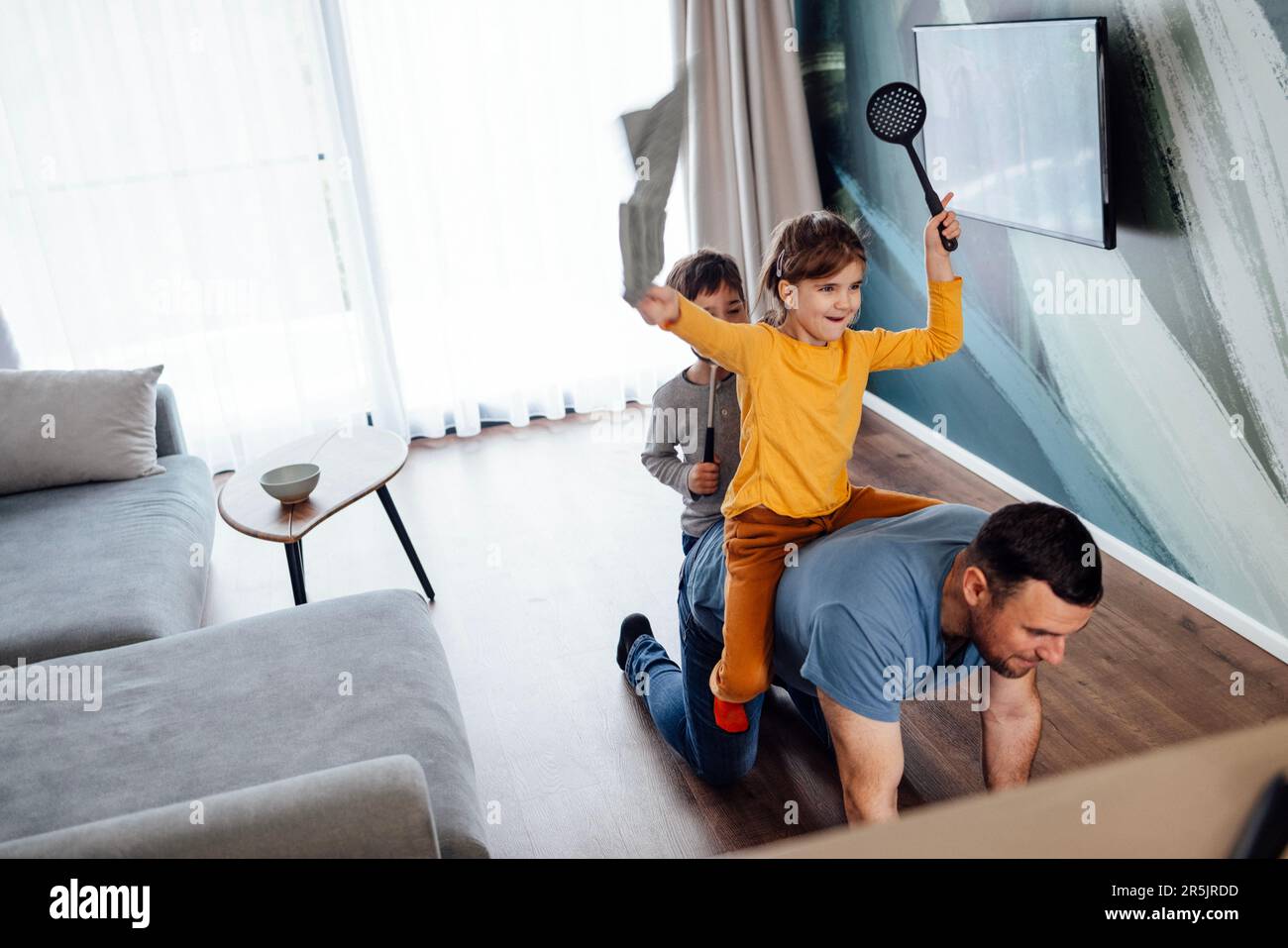 Funny cute laughing girl is riding on her dad and waving towel ...