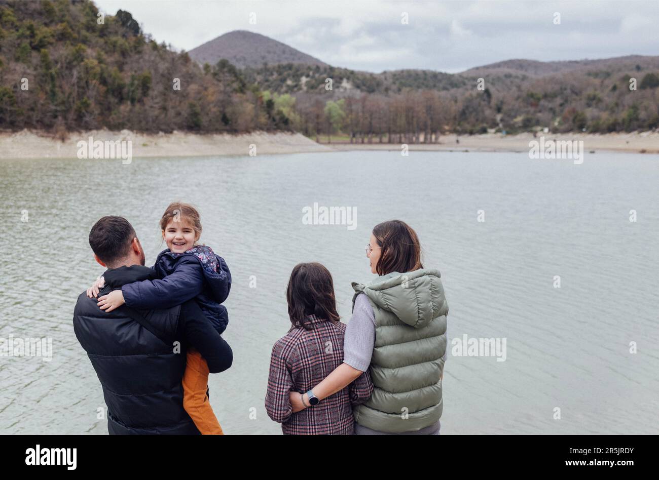 Happy family with two children by lake. People are dressed in warm ...