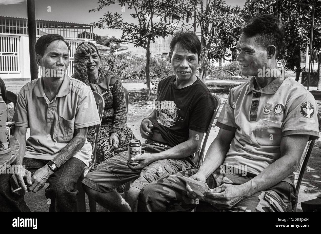 Three men and one woman from the Brau ethinic minority sit together in ...