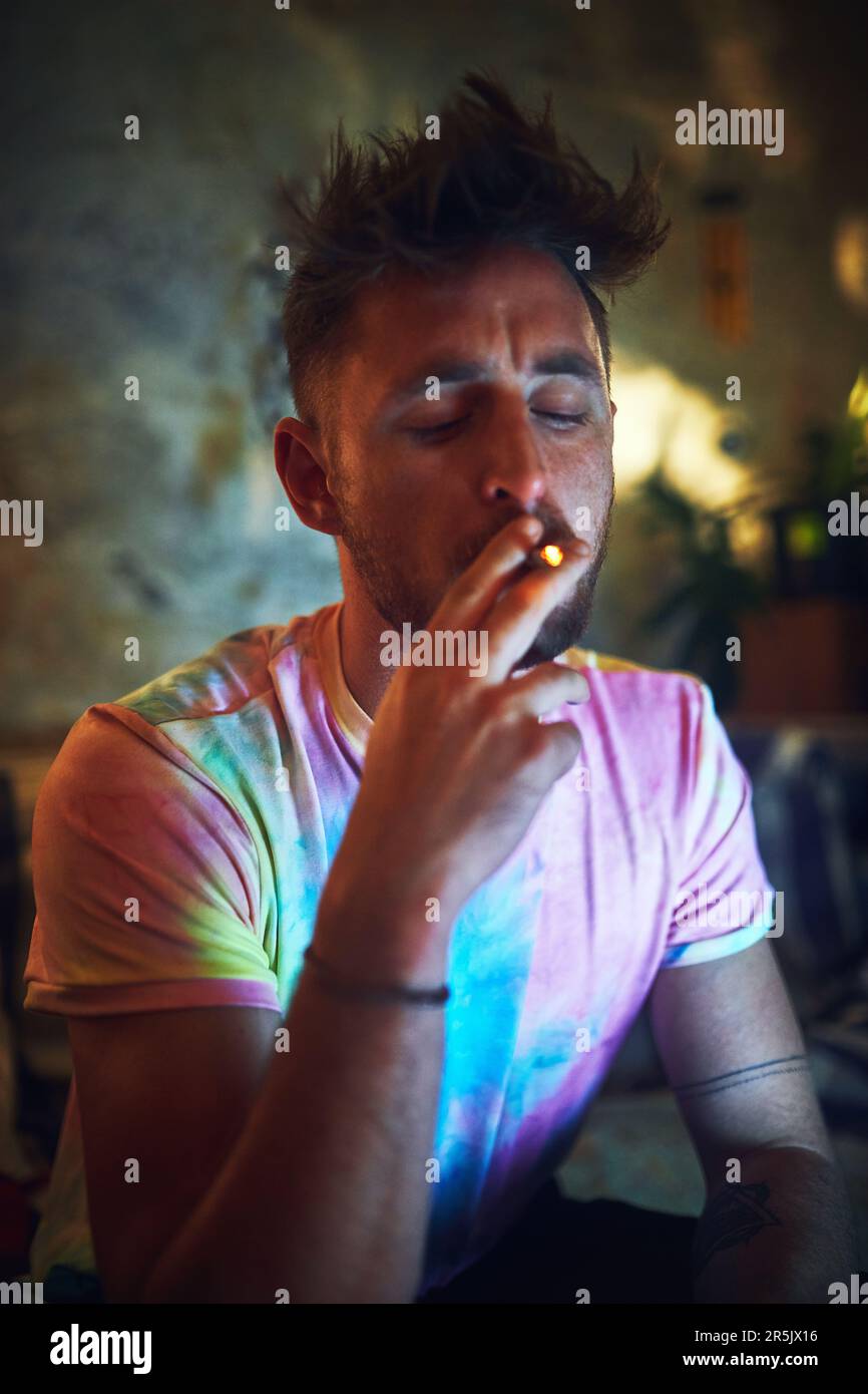 Smoking his special cigarette. a handsome young man smoking a blunt of ...