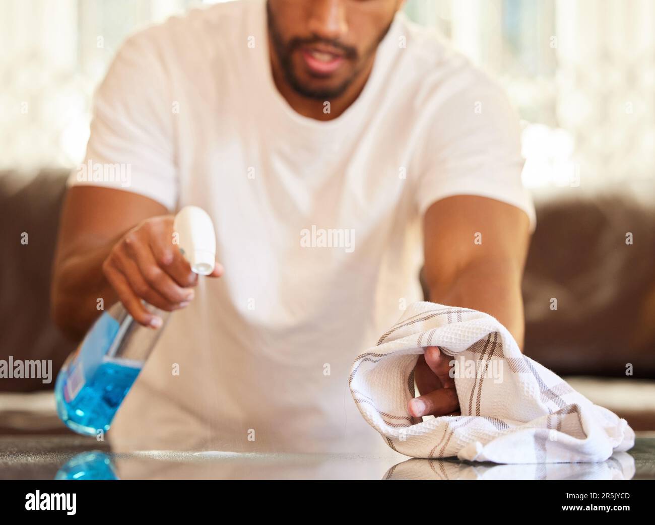 Man, clean table with spray and cloth, chemical detergent and wipe dirt ...