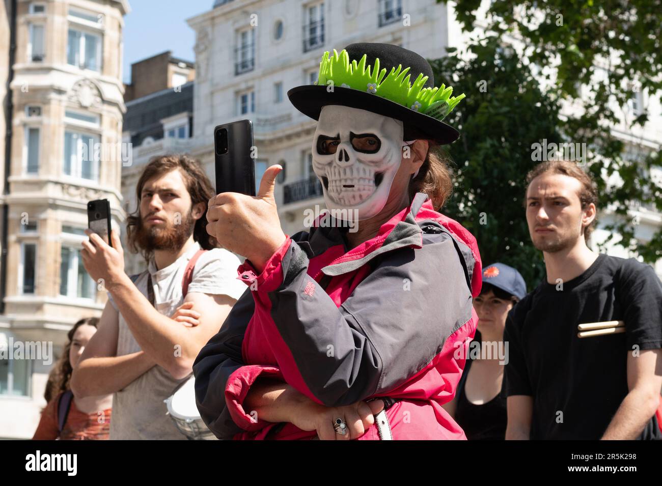 London, UK. 4 June, 2023. A protester wearing a skull mask films events ...