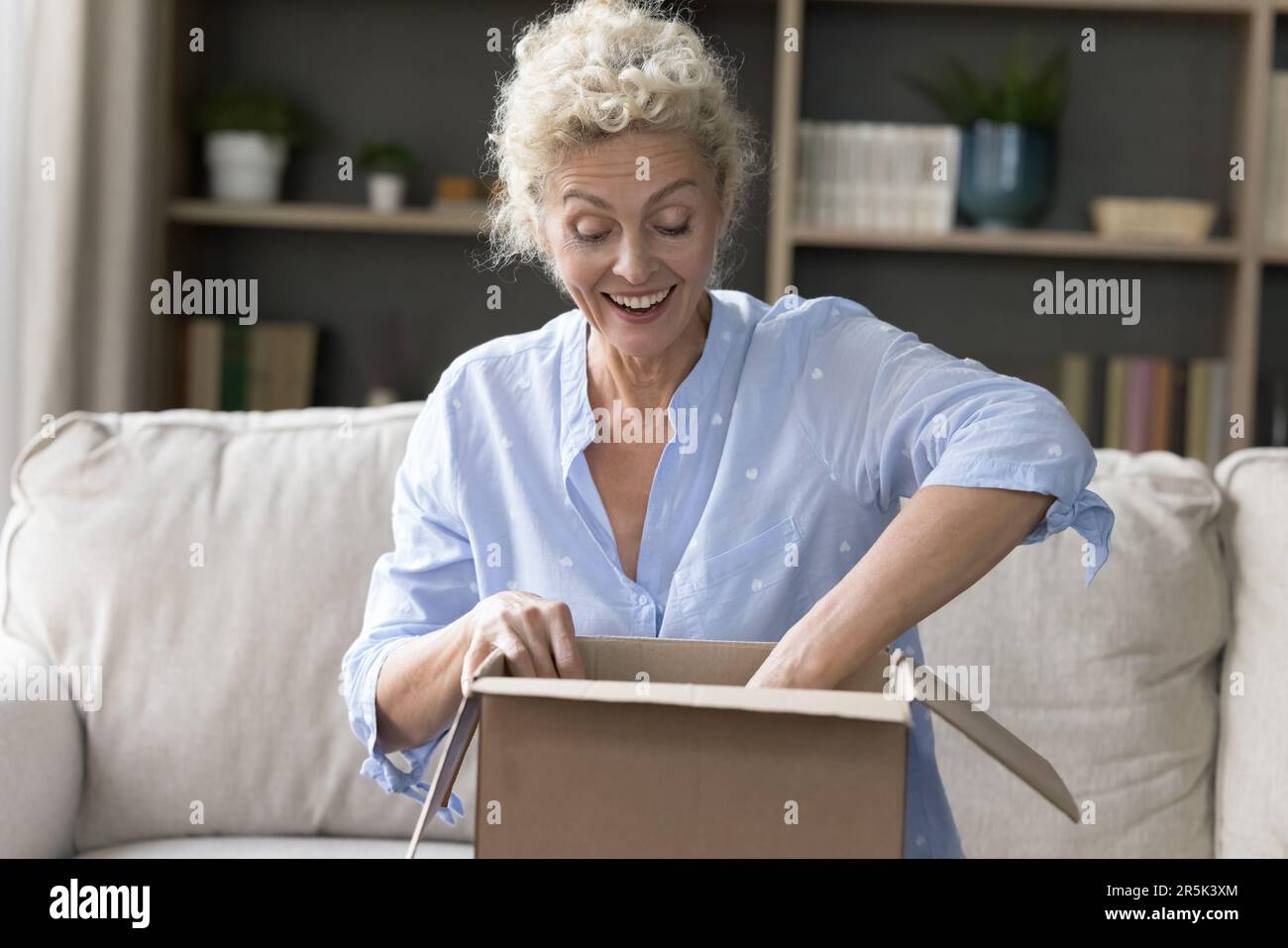 Happy surprised online shop customer woman opening parcel Stock Photo ...