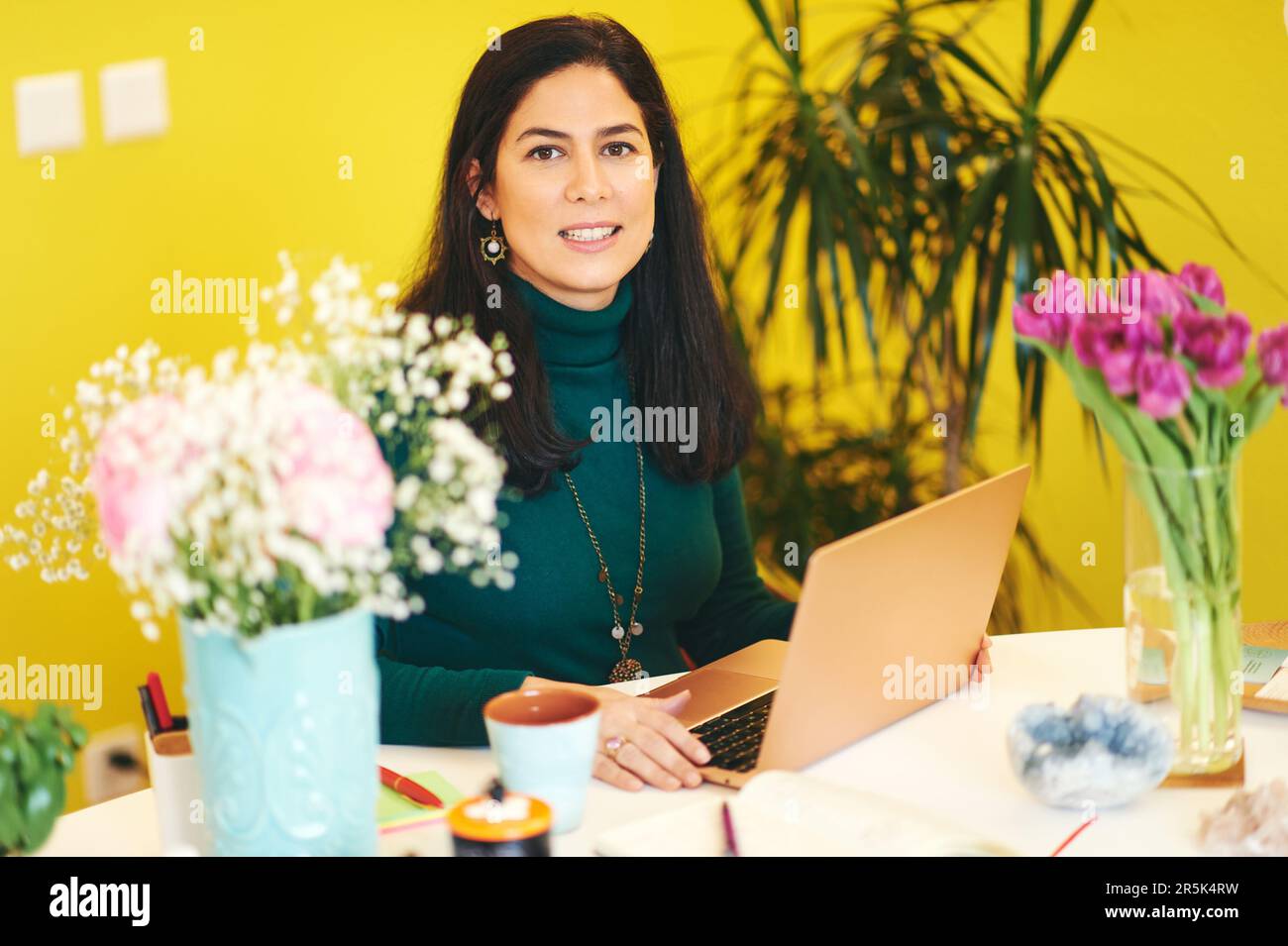 Beautiful middle age woman working in colorful cosy office, using ...