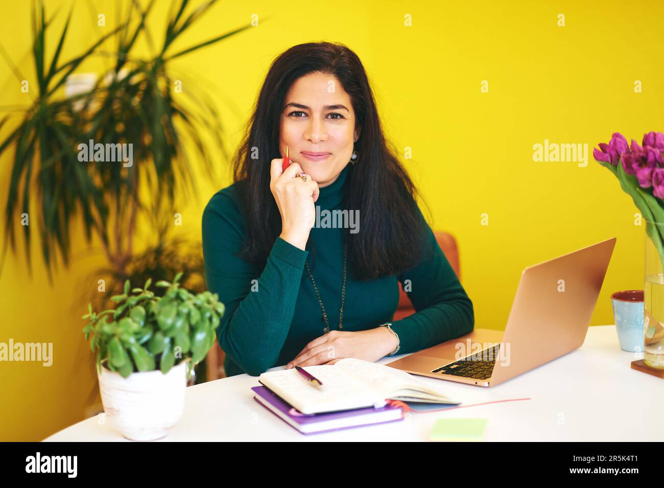 Beautiful middle age woman working in colorful cosy office, using ...