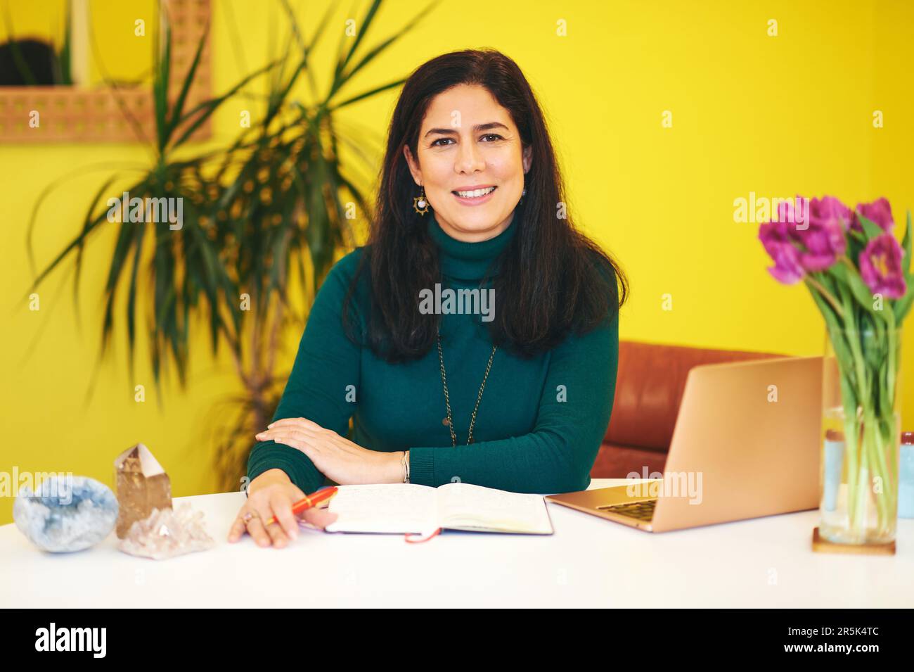 Beautiful middle age woman working in colorful cosy office, using ...