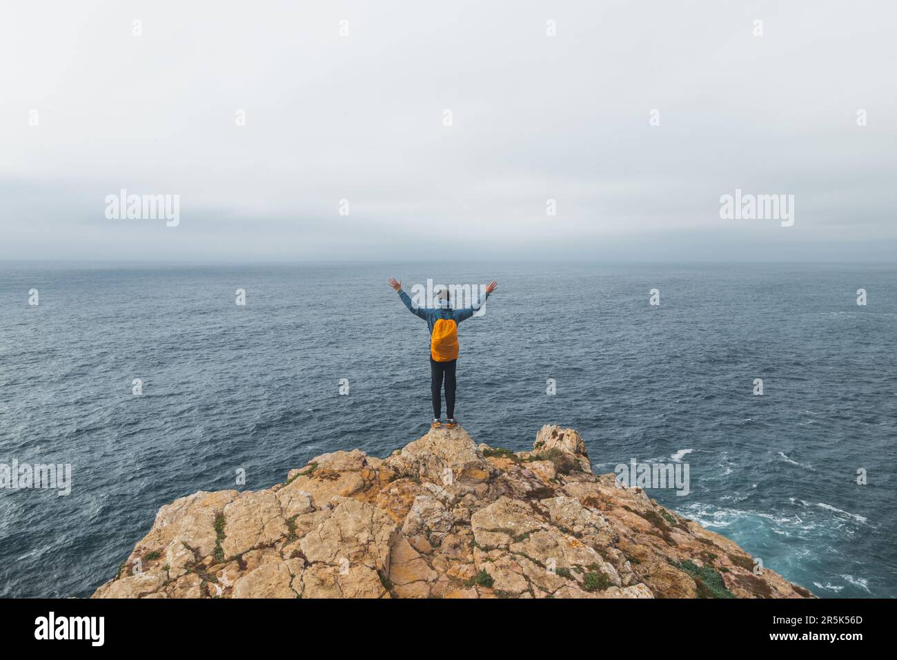 Black-haired adventurer stands at the end of Cape Cabo de Sao Vicente ...