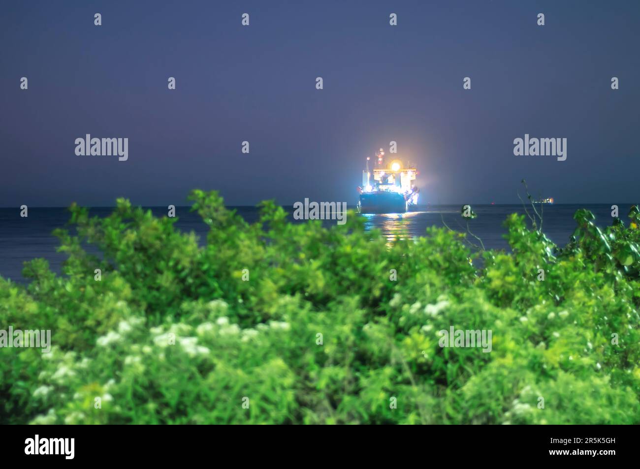Cargo ship sailing at sea at night with lights on,photo on long ...