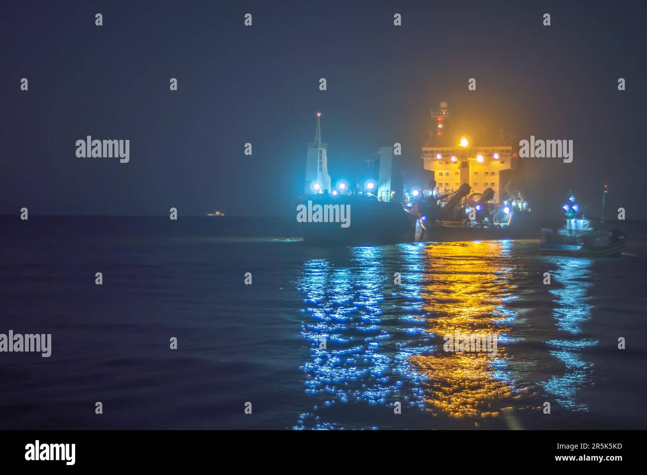 Cargo ship sailing at sea at night with lights on,photo on long ...