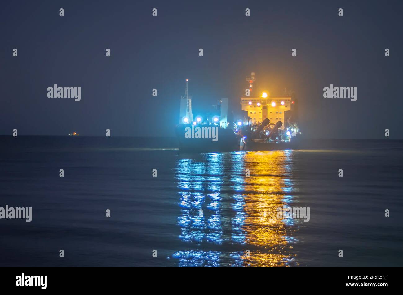 Cargo ship sailing at sea at night with lights on,photo on long ...