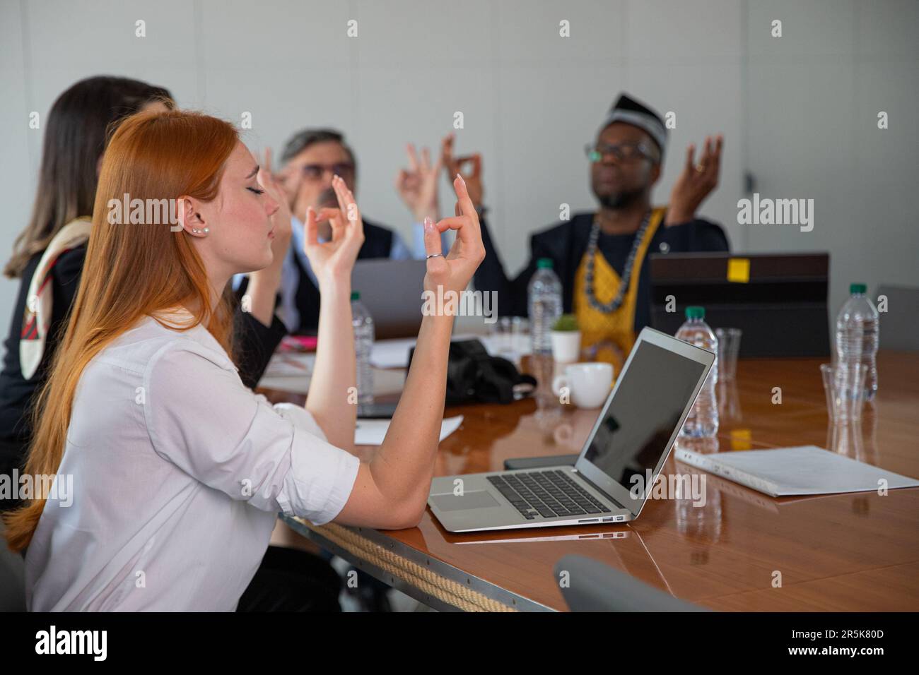 A multi ethnic group of business people do yoga exercises to relax in ...