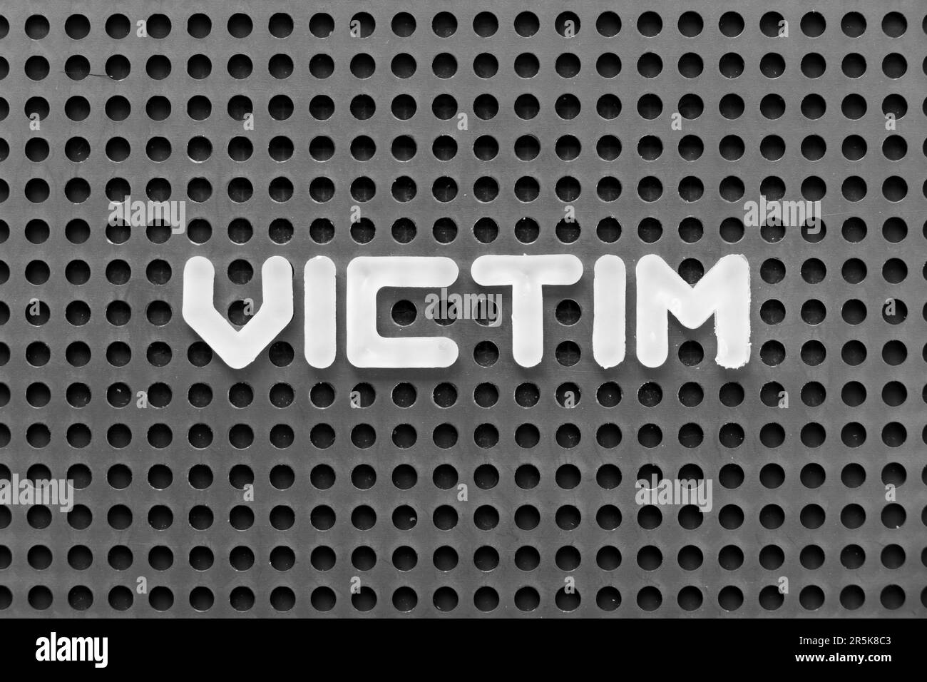 White alphabet letter in word victim on black pegboard background Stock ...