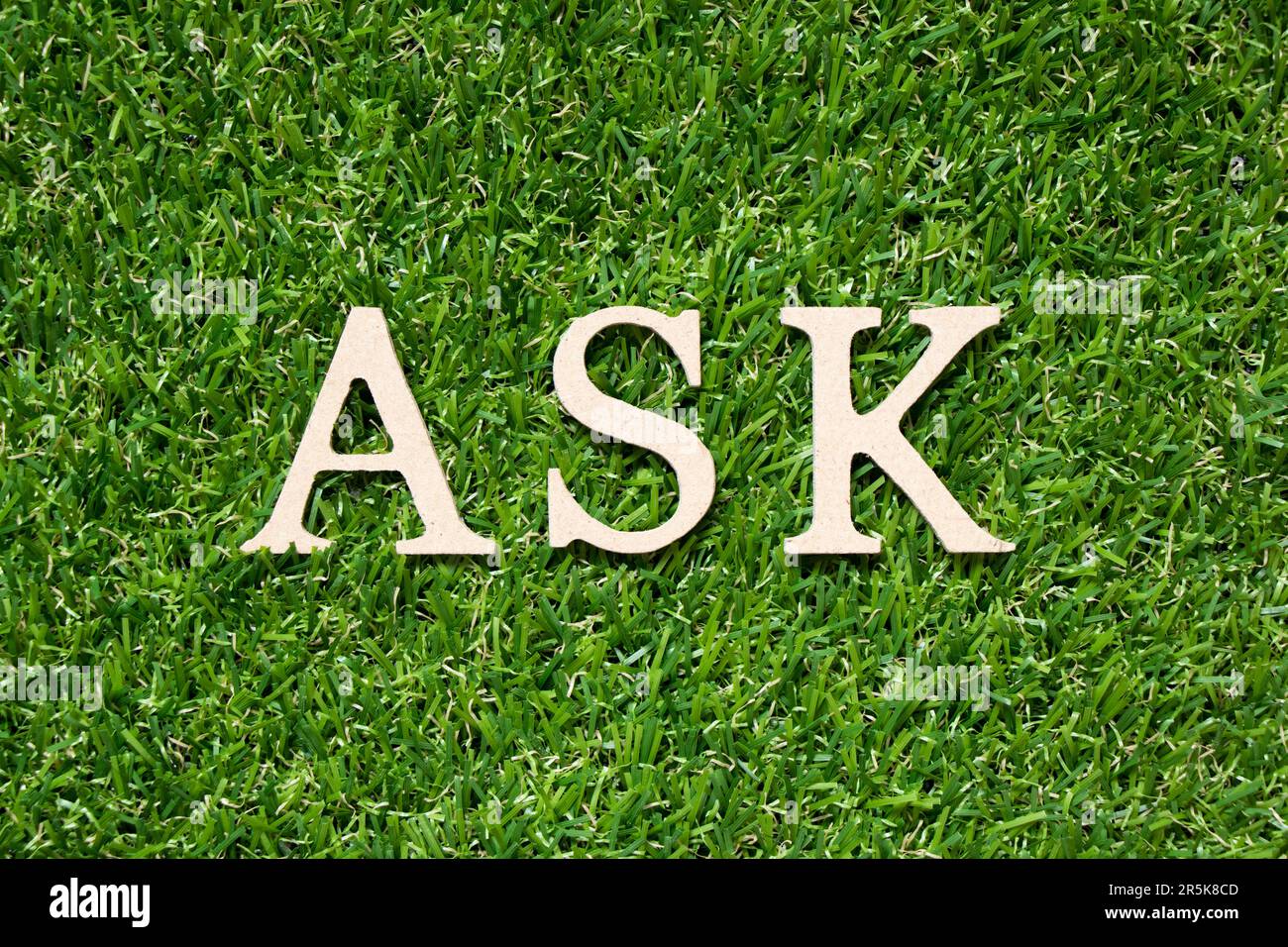 Wood alphabet letter in word ask on artificial green grass background ...