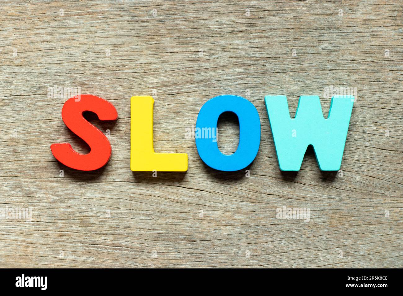 Color alphabet letter in word slow on wood background Stock Photo - Alamy