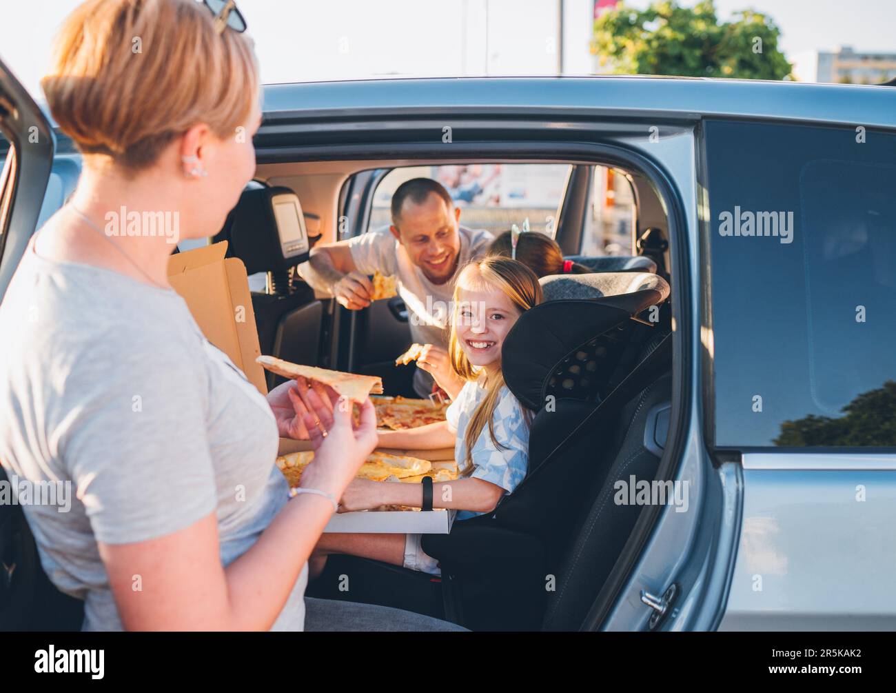 Positive smiling girl in child car seat while family car trip brake ...