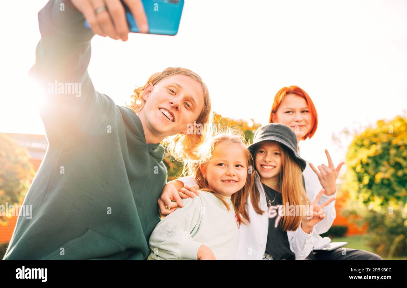 Portraits of three smiling sisters and brother teen taking selfie ...