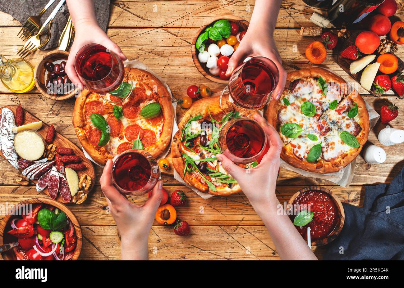 Pizza party with friends. Top view people holding glasses with red wine ...