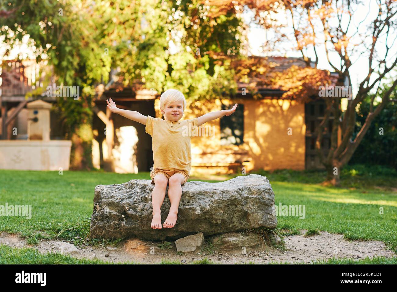 Adorable toddler boy playing in summer park, pretending to be a plane ...