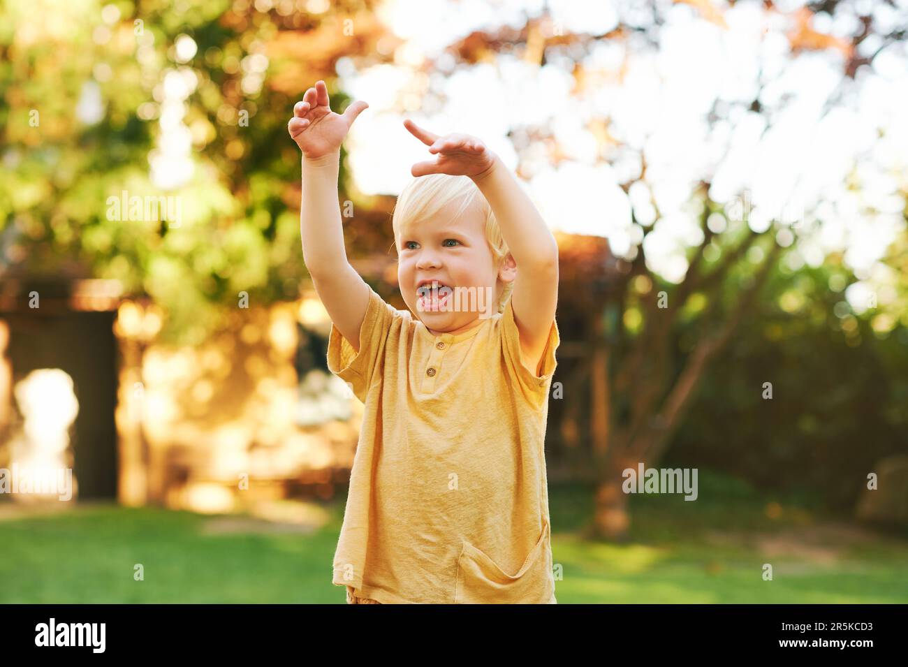 Outdoor portrait of excited toddler boy playing in summer sunny park ...