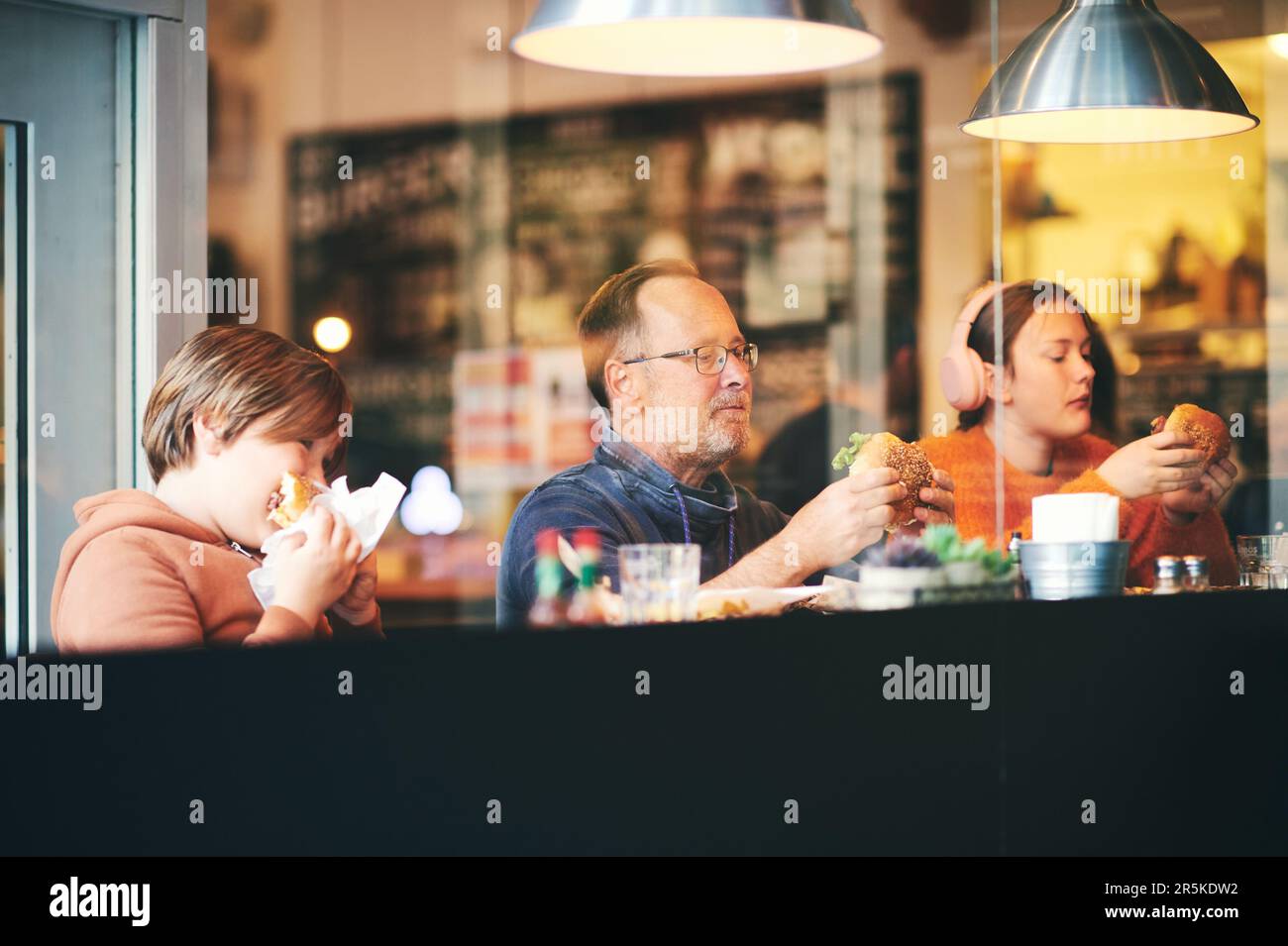 Family lunch, father with children eating hamburgers, in restaurant ...