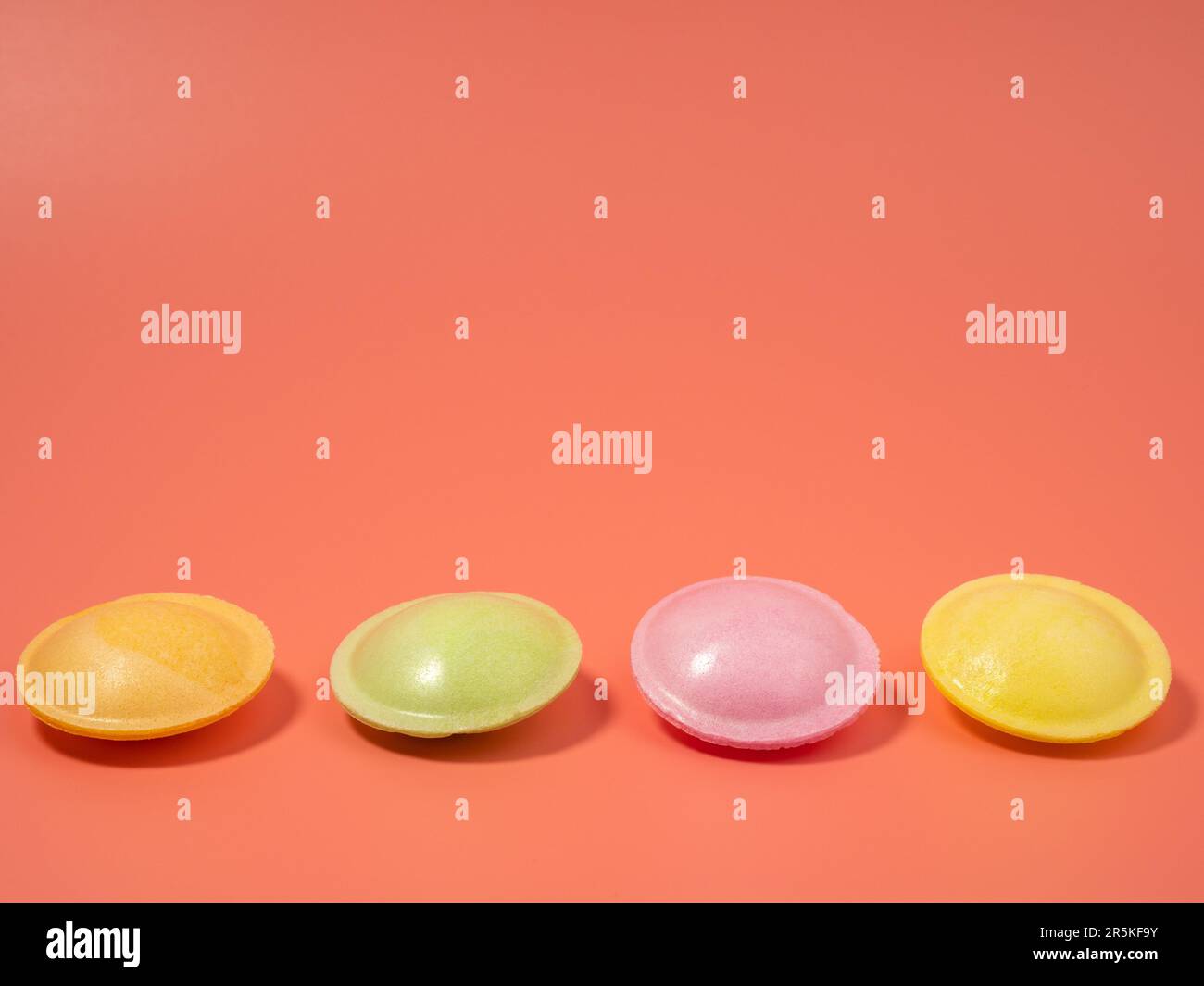 Sweet candies in the shape of a UFO in different colors on a pink ...
