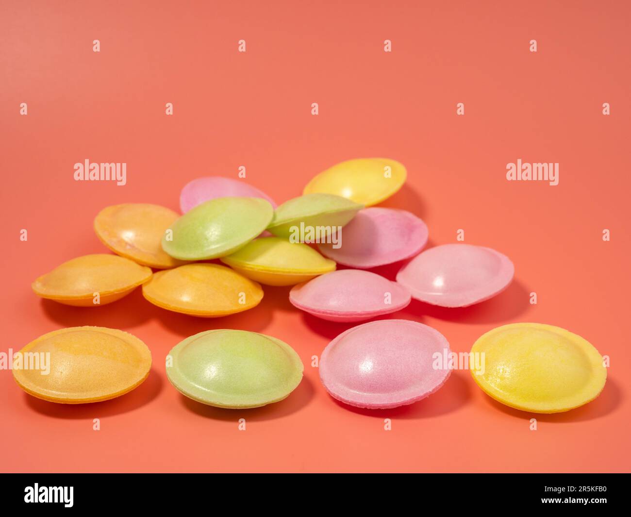 Sweet candies in the shape of a UFO in different colors on a pink ...