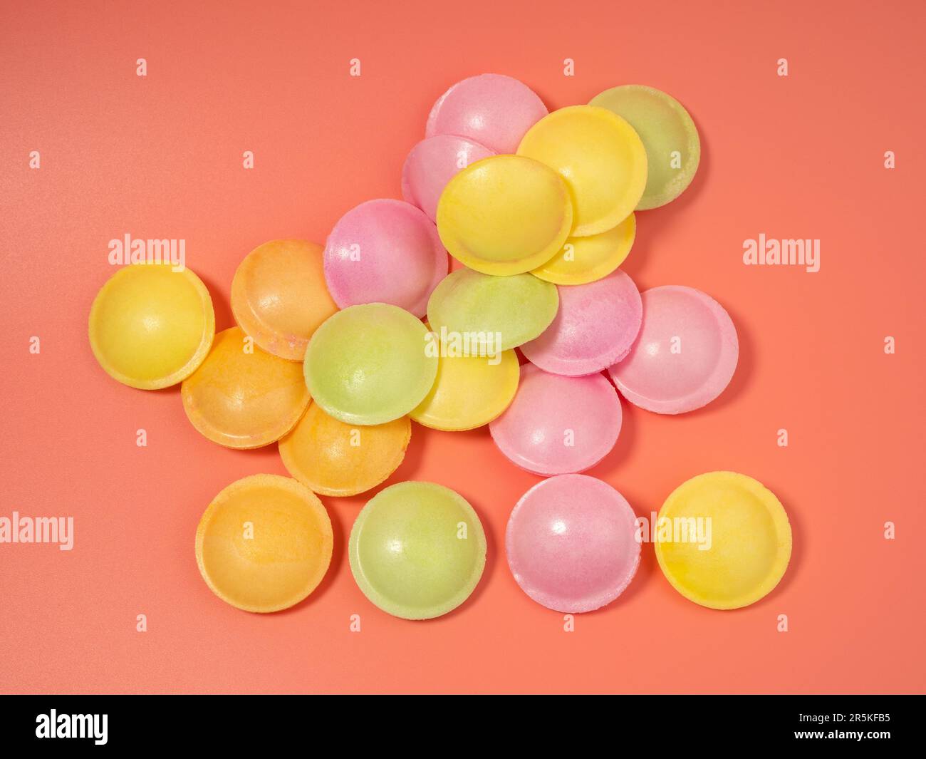 Sweet candies in the shape of a UFO in different colors on a pink ...
