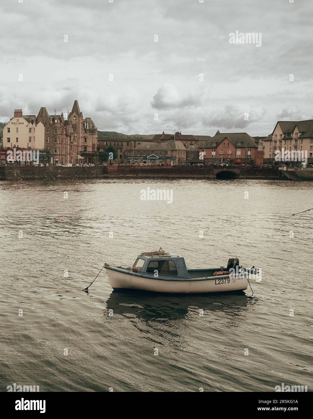 In a picturesque Scottish harbor, a boat gently bobs on the calm waters ...