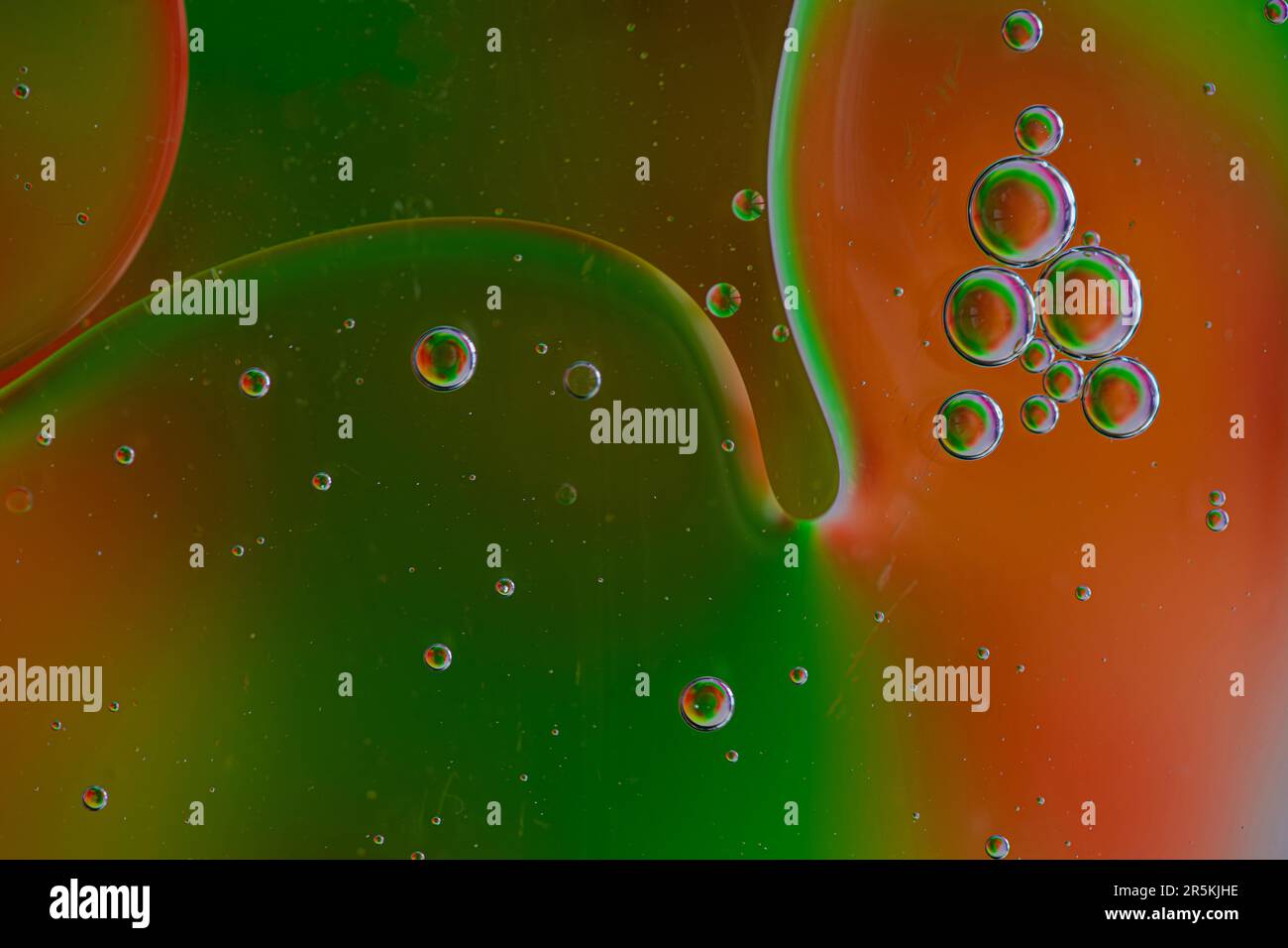 Oil floating on water with green and orange background Stock Photo - Alamy