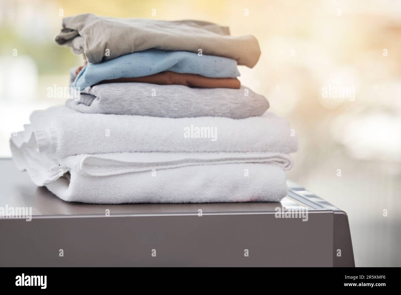 Home, clothes on a washing machine and laundry day with a lens flare ...