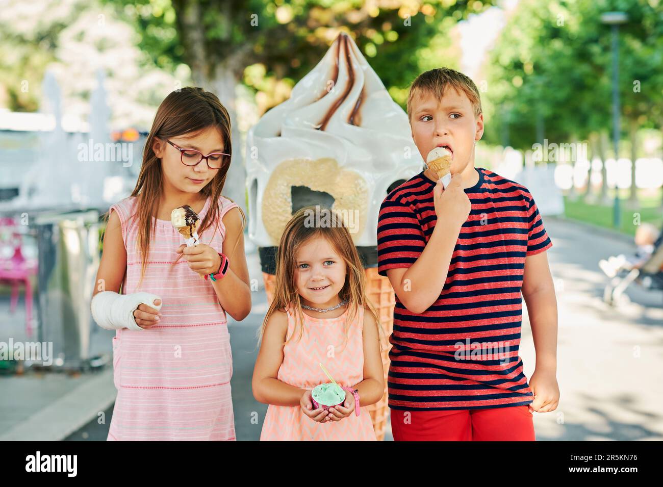 Group of 3 funny kids eating ice cream outdoors on a nice sunny day ...