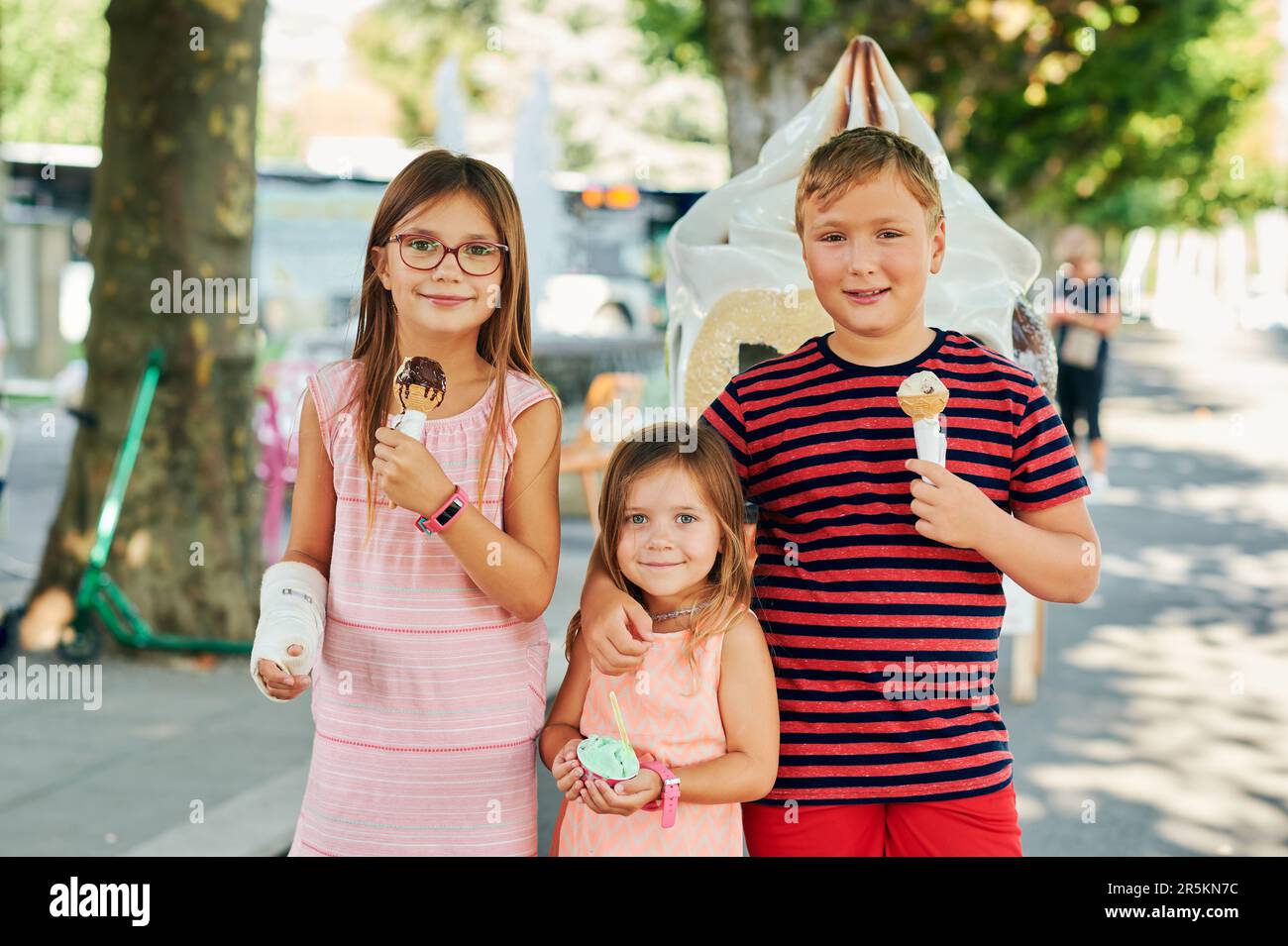 Group of 3 funny kids eating ice cream outdoors on a nice sunny day ...