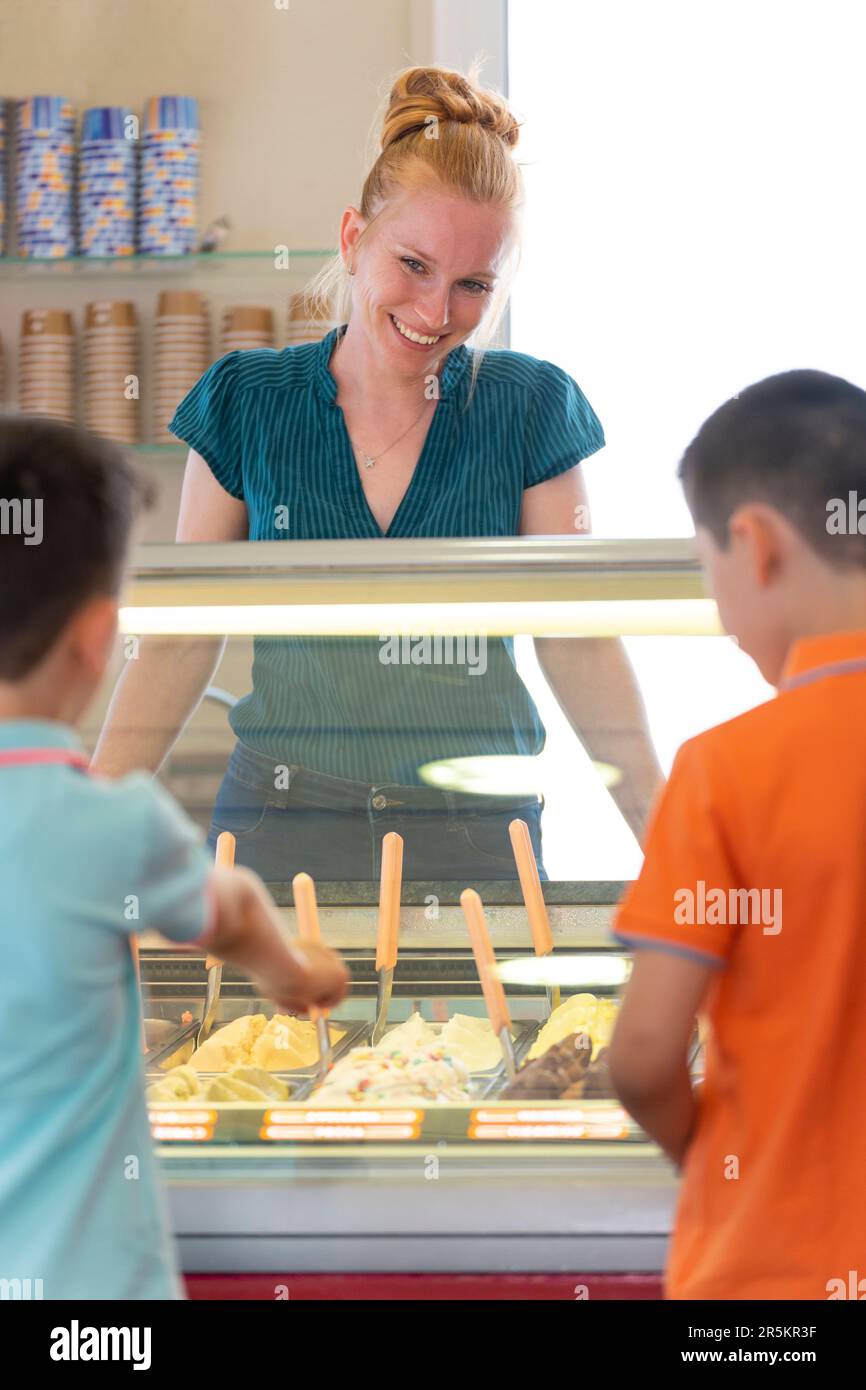Ice cream shop assistant serving two children Stock Photo - Alamy