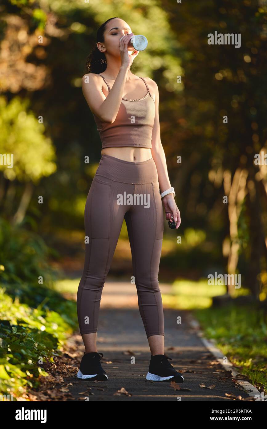 Fitness, woman and drinking water in nature for rest, sustainability or ...